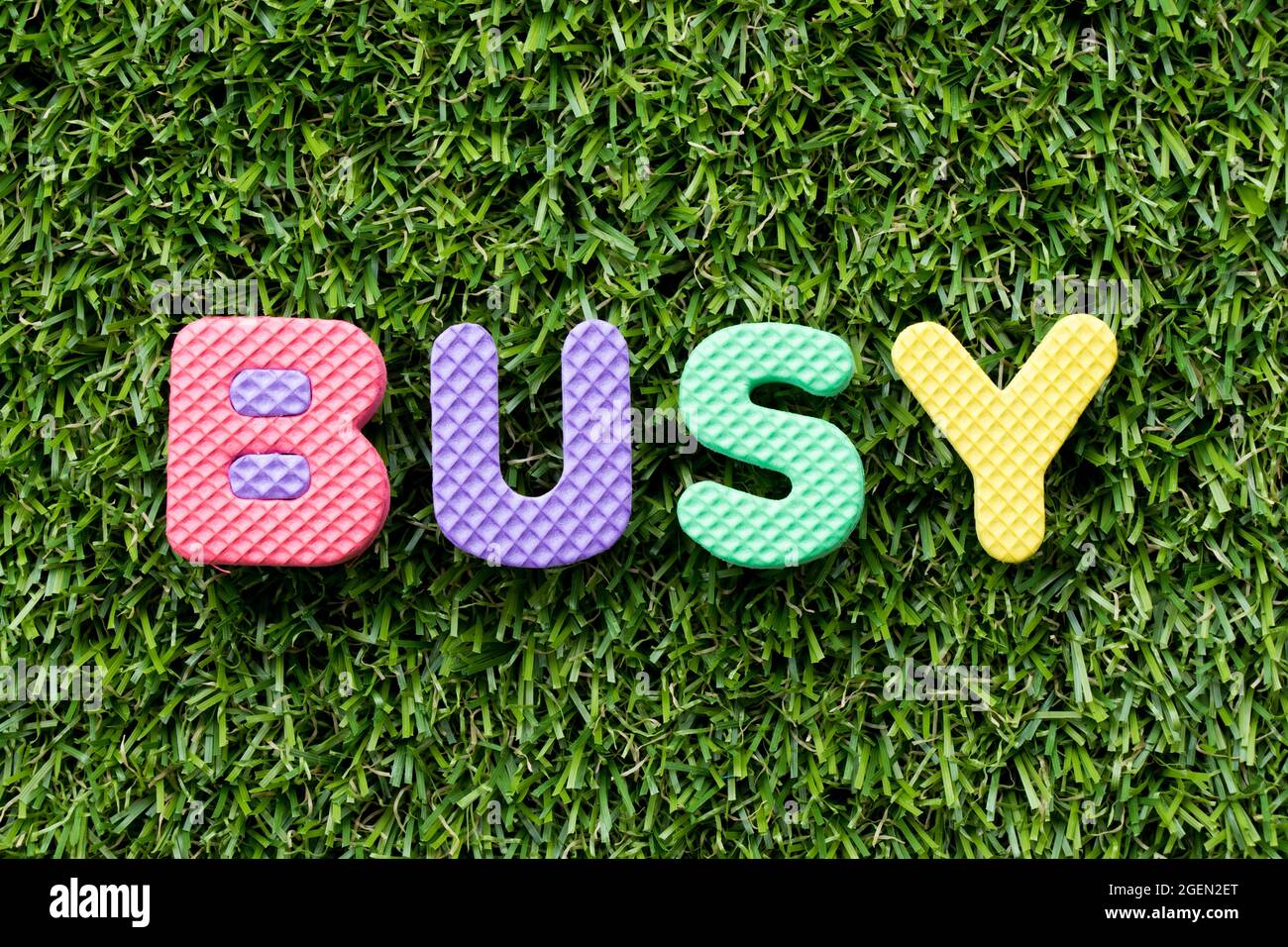 Color alphabet letter in word busy on artificial green grass background ...
