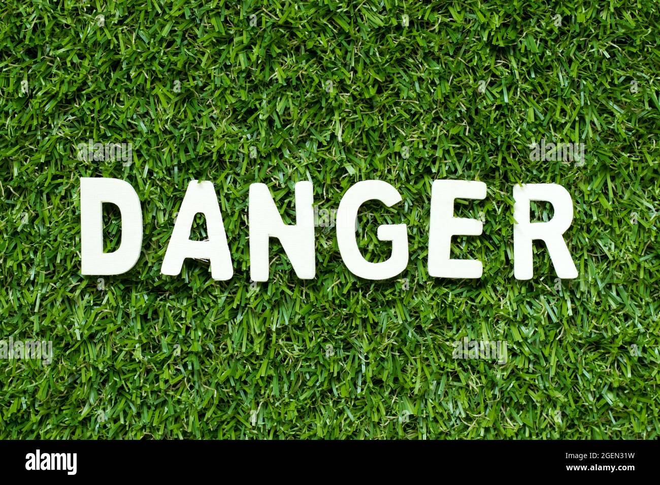 Alphabet letter in word danger on artificial green grass background ...