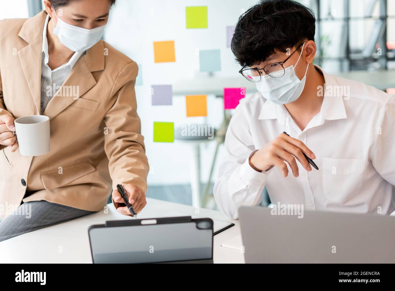 Two colleagues wearing surgical masks analyzing the data in chart for ...