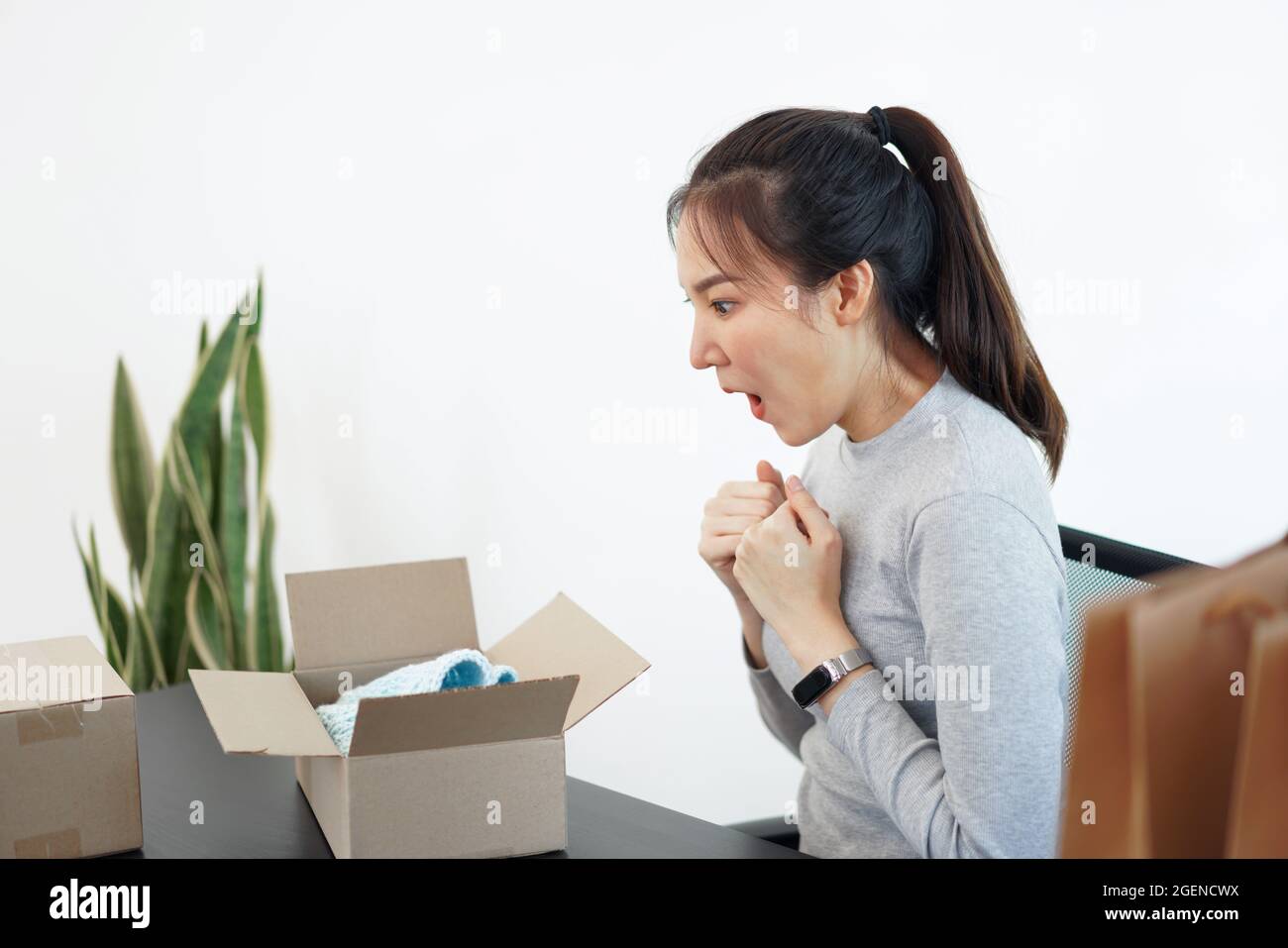 Shopping online concept a smiling woman unboxing an arriving parcel to ...