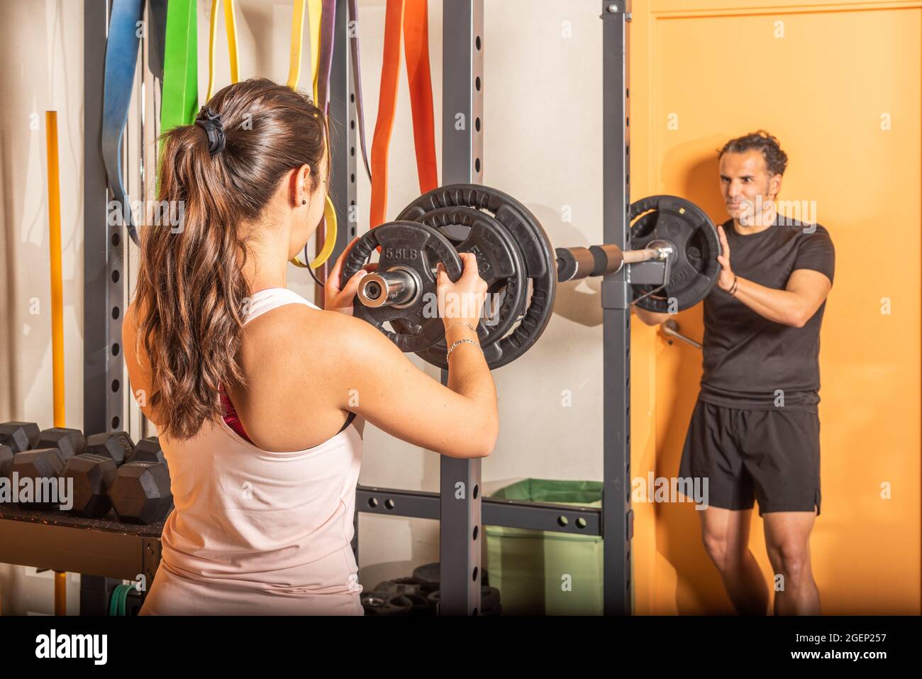 Man and woman putting weight plate on bar in gym Stock Photo - Alamy