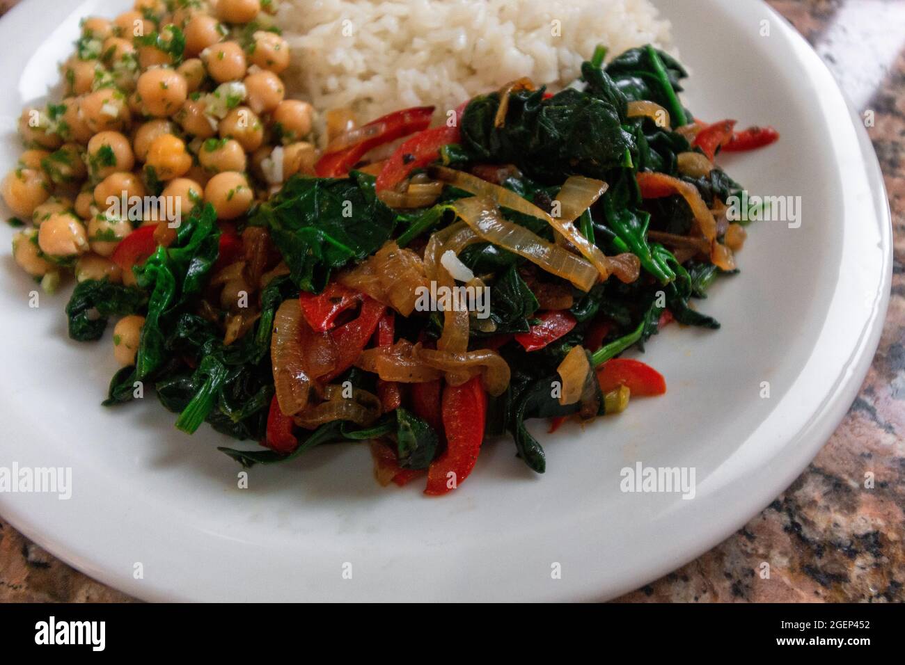 Closeup of a plate with rice, chickpea, and a cooked spinach salad ...