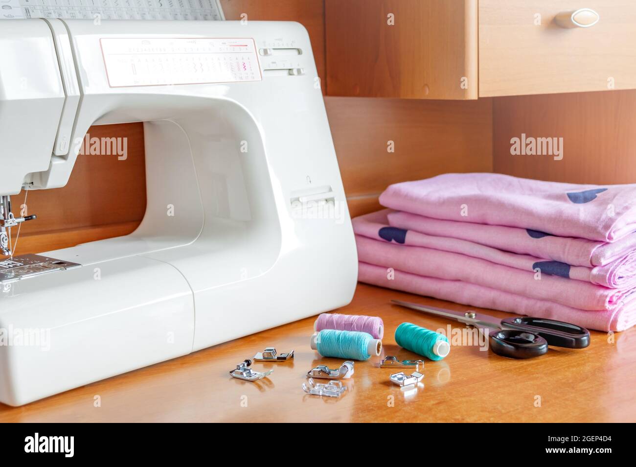 Sewing machine, textile, presser feet, threads, scissors on the table ...
