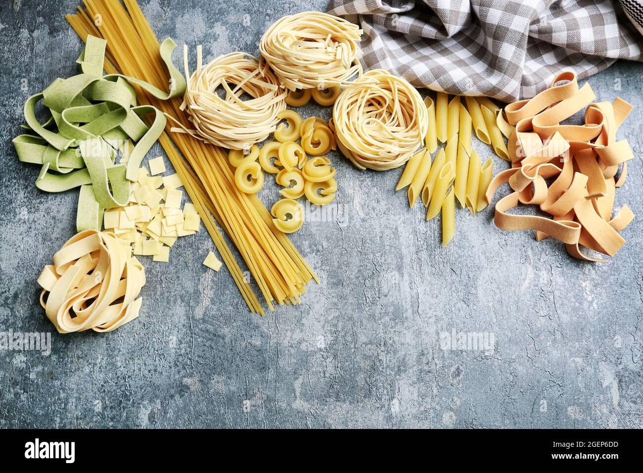 Mixed types and shapes of italian pasta on grey stone, background. Copy ...