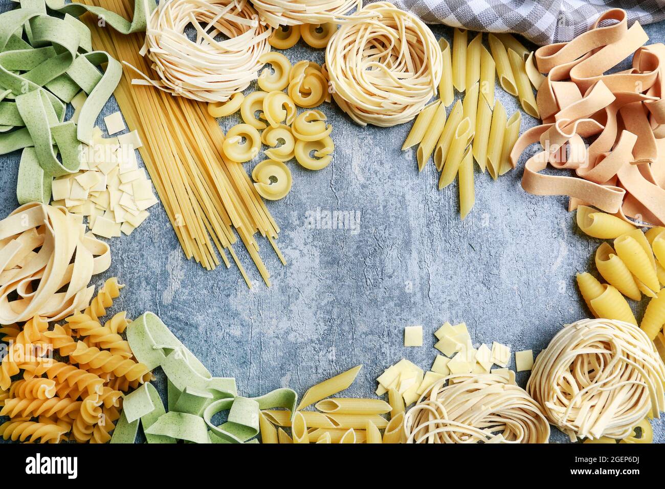 Mixed types and shapes of italian pasta on grey stone, background. Copy ...