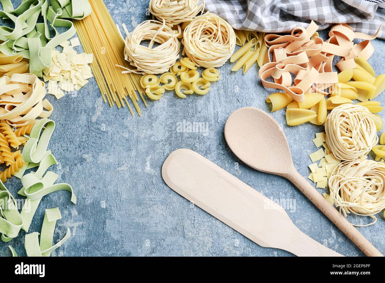 Mixed types and shapes of italian pasta on grey stone, background. Copy ...
