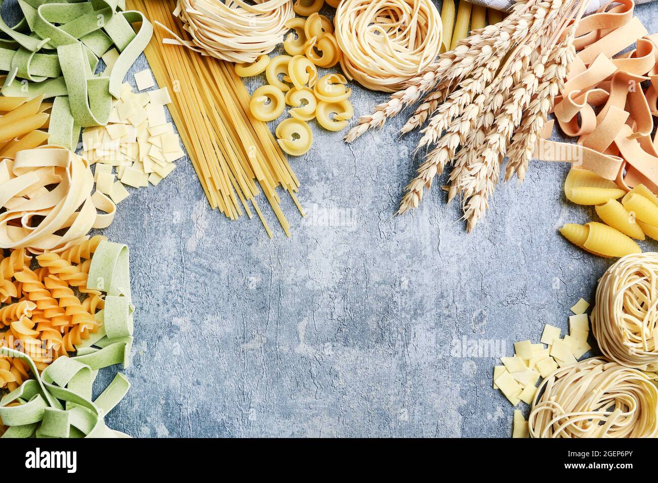 Mixed types and shapes of italian pasta on grey stone, background. Copy ...