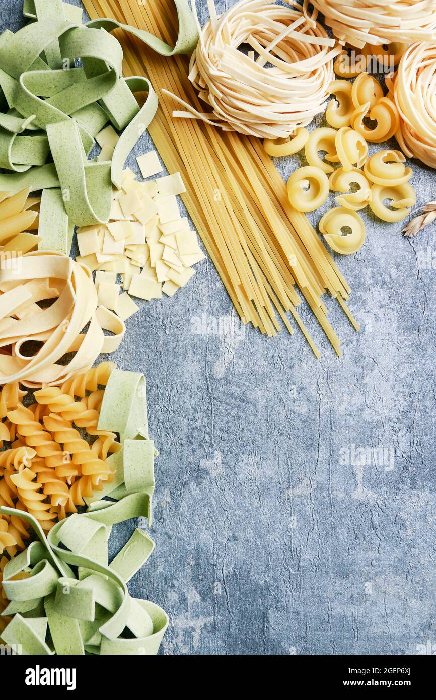 Mixed types and shapes of italian pasta on grey stone, background. Copy ...