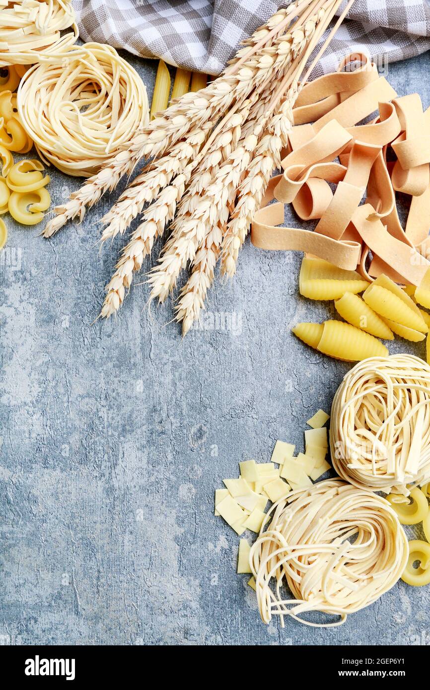 Mixed types and shapes of italian pasta on grey stone, background. Copy ...