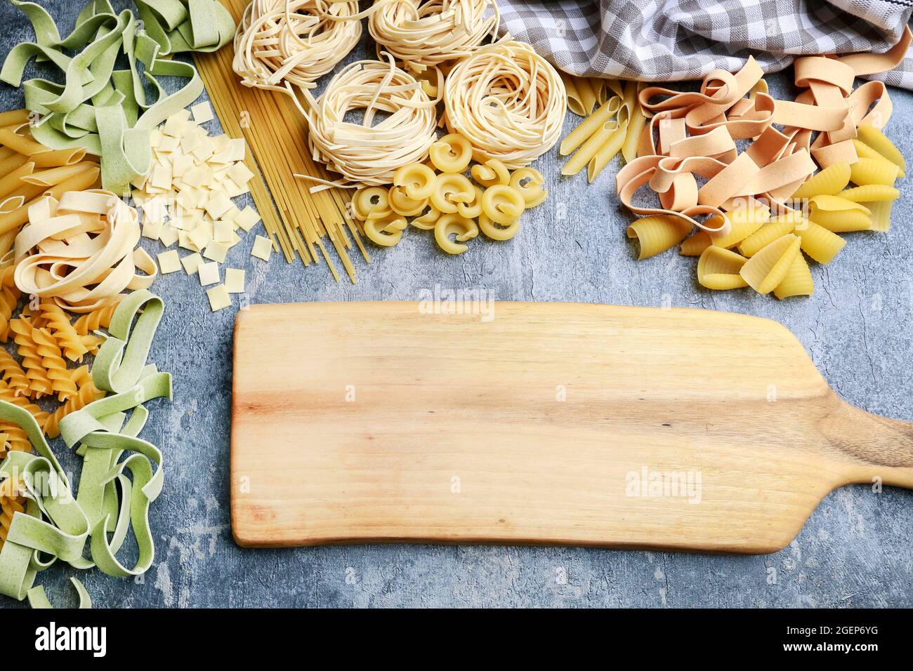 Mixed types and shapes of italian pasta on grey stone, background. Copy ...