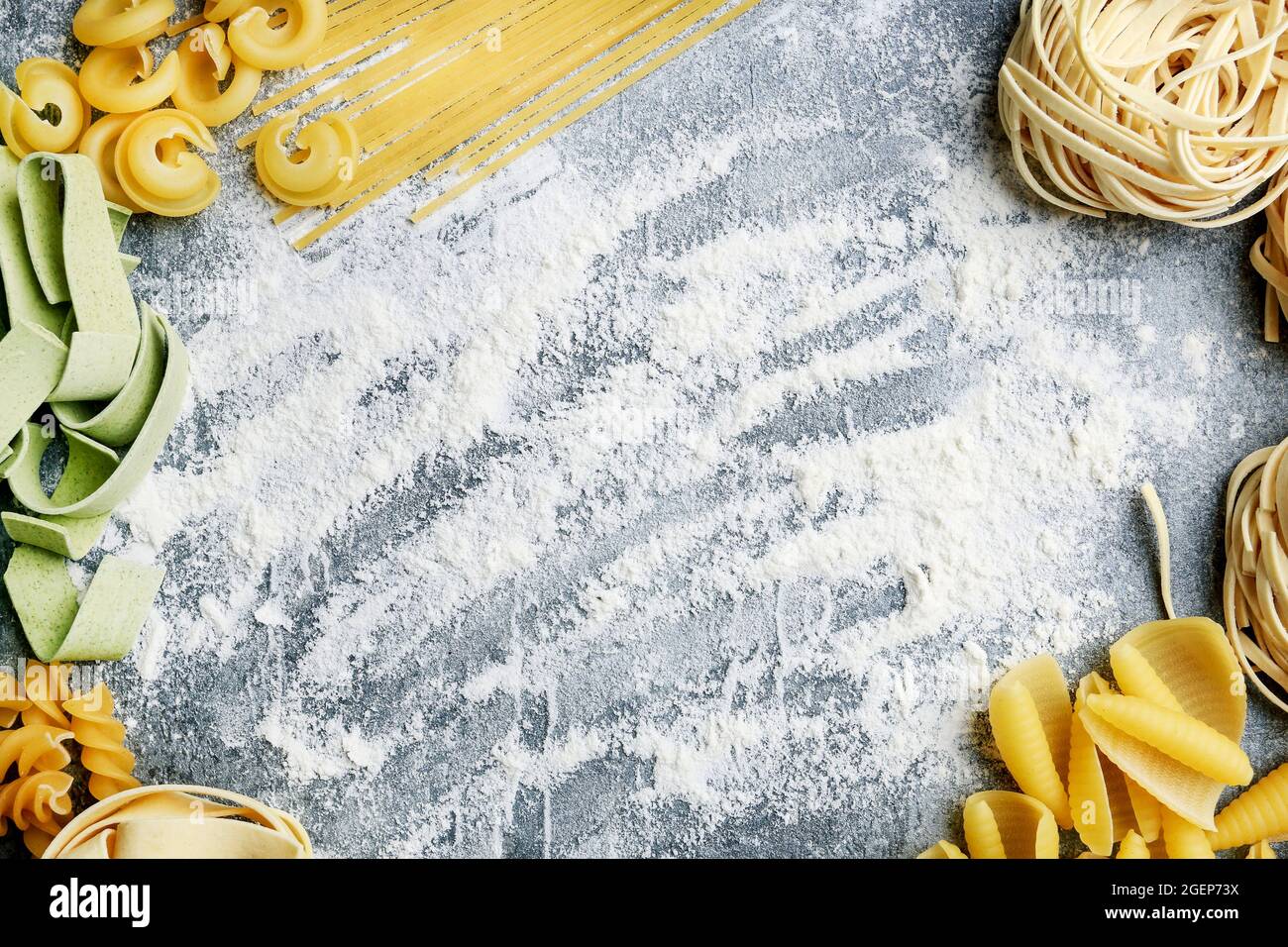 Mixed types and shapes of italian pasta on grey stone, background. Copy ...