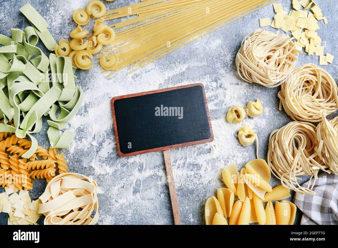 Mixed types and shapes of italian pasta on grey stone, background. Copy ...
