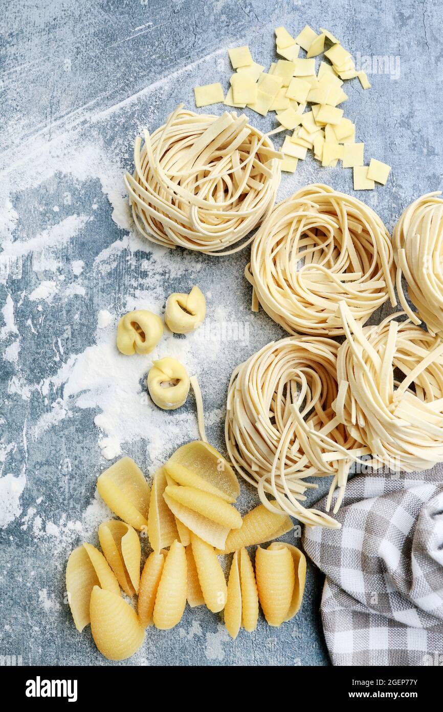 Mixed types and shapes of italian pasta on grey stone, background. Copy ...