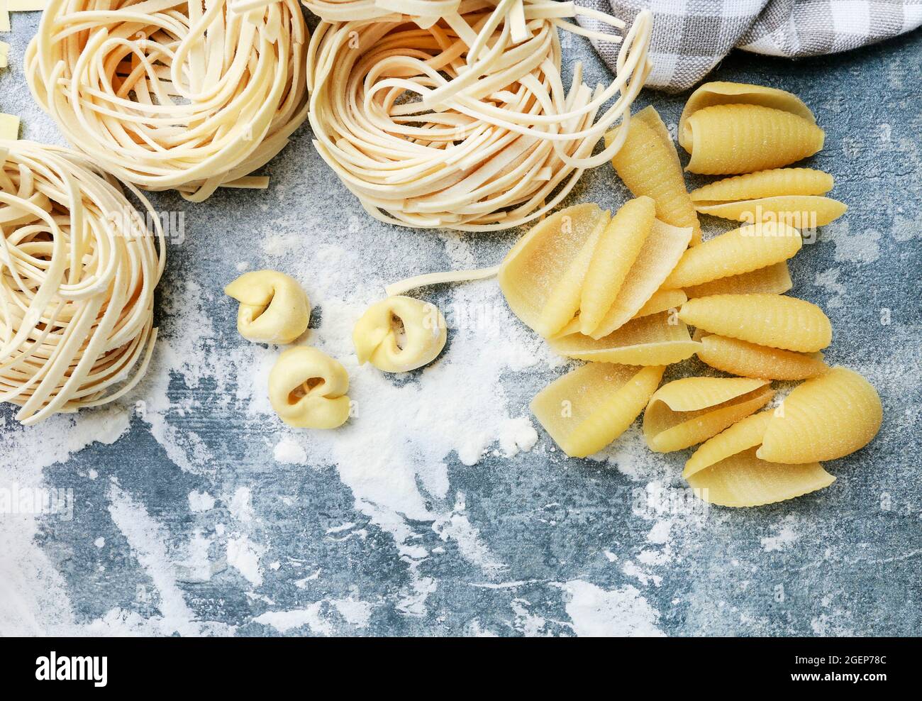 Mixed types and shapes of italian pasta on grey stone, background. Copy ...