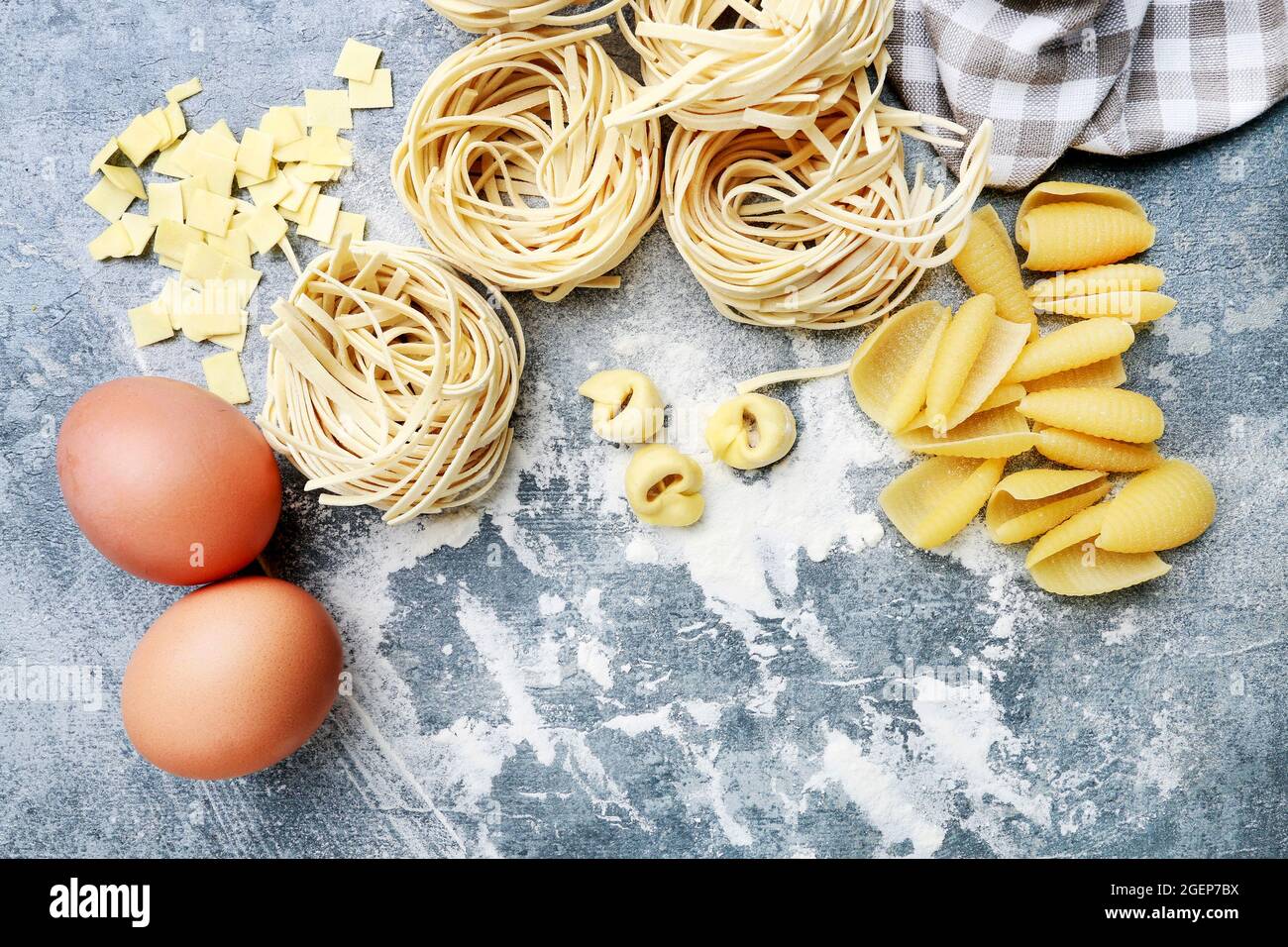 Mixed types and shapes of italian pasta on grey stone, background. Copy ...