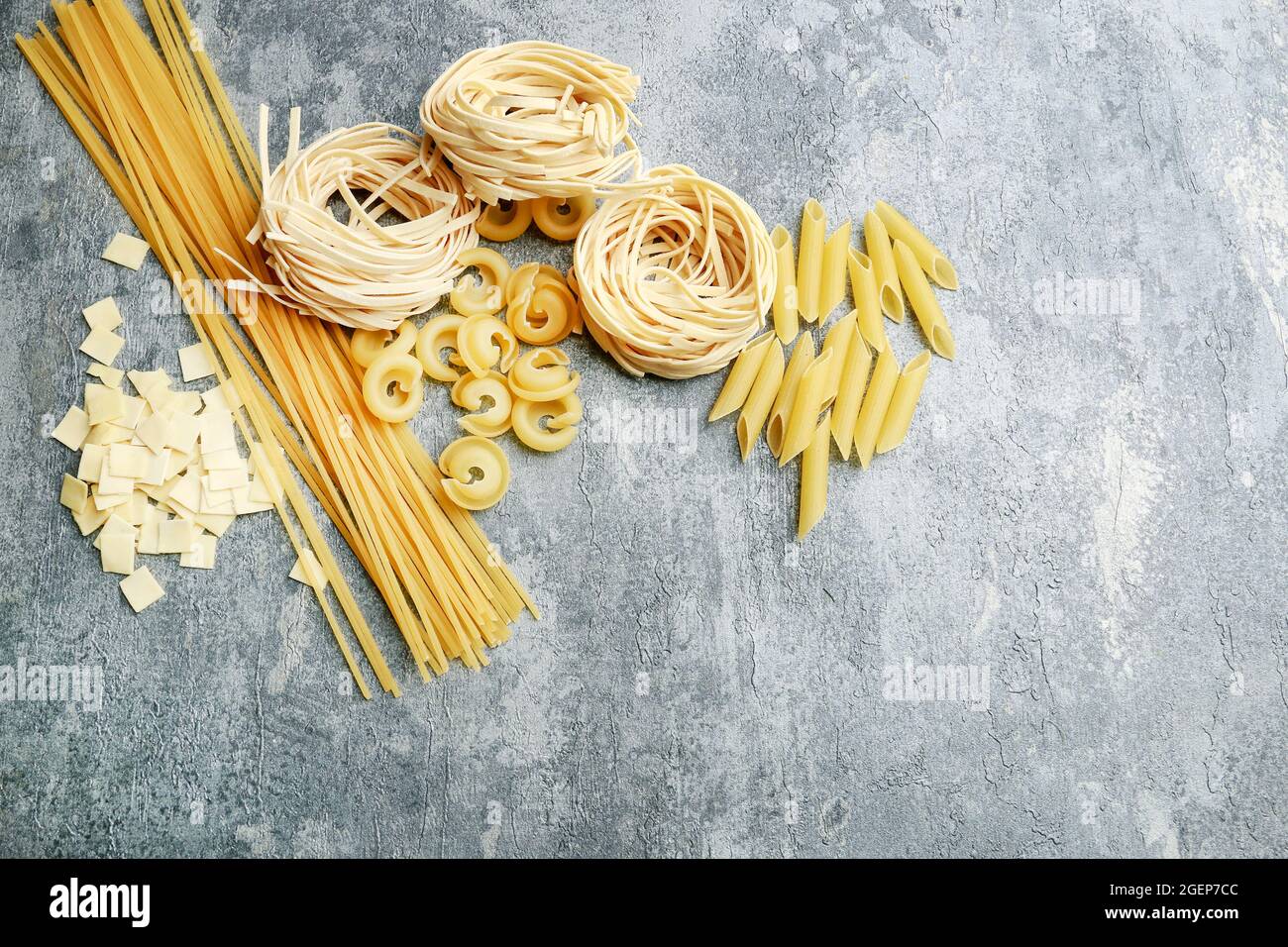 Mixed types and shapes of italian pasta on grey stone, background. Copy ...