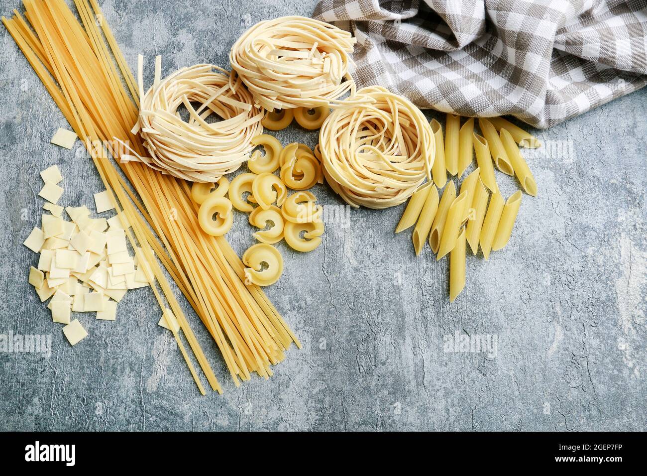 Mixed types and shapes of italian pasta on grey stone, background. Copy ...