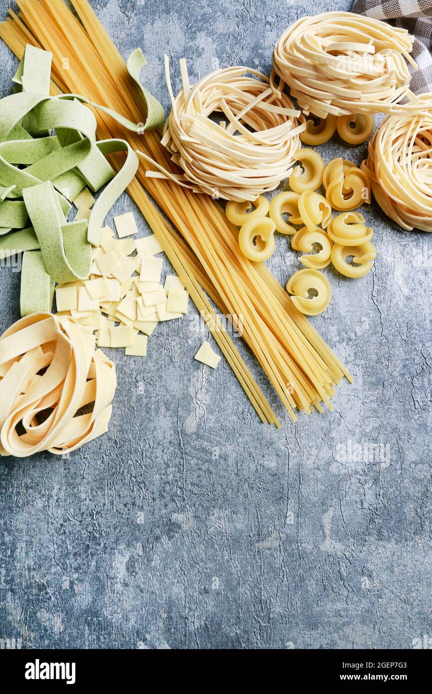 Mixed types and shapes of italian pasta on grey stone, background. Copy ...