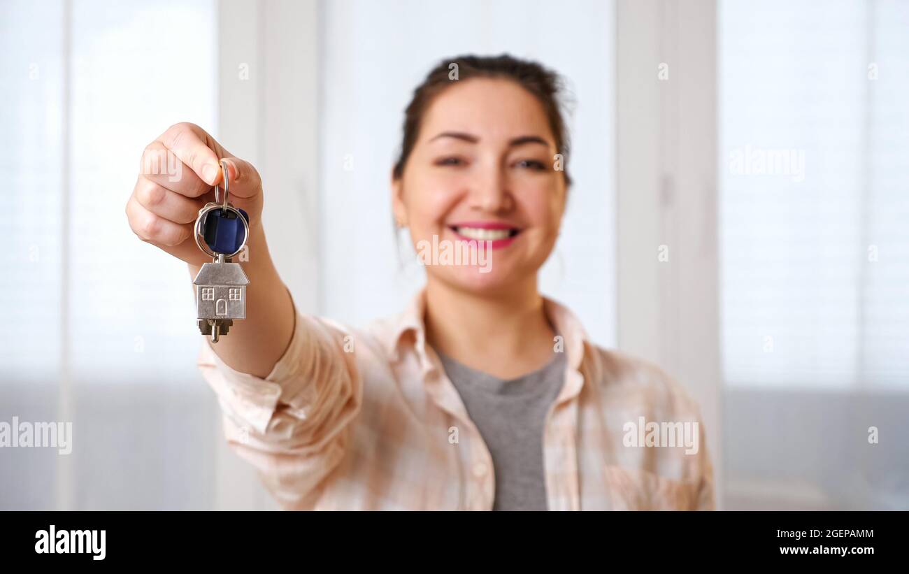 Smiling woman shows keys with house breloque near window Stock Photo ...