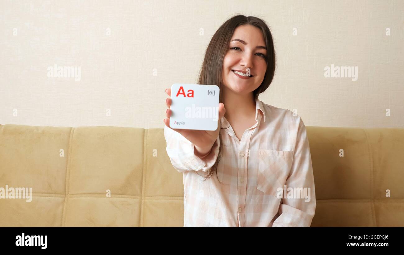 Young woman demonstrates cards with letters of the English alphabet and ...