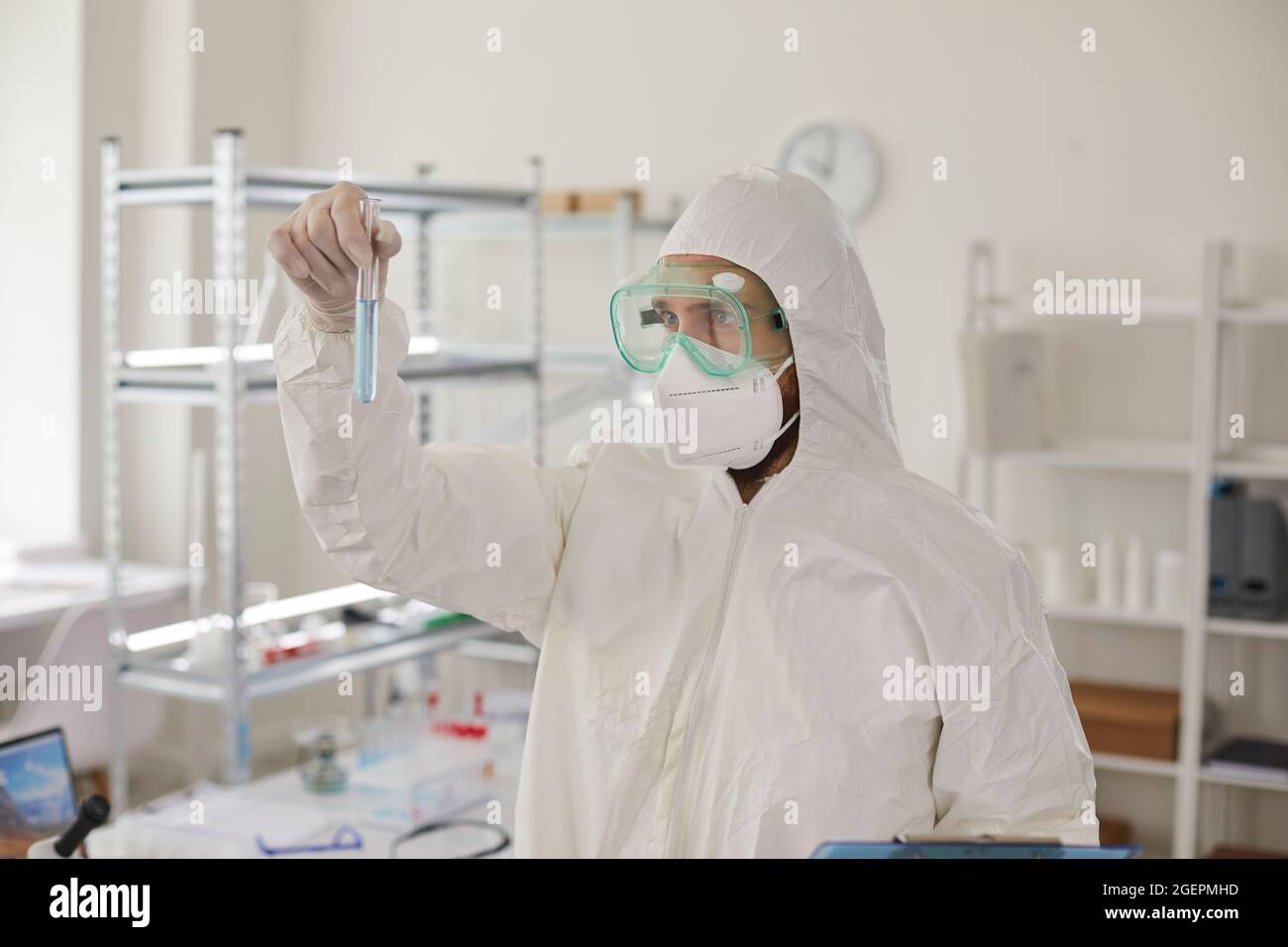 Biologist in protective laboratory clothing looks intently at a test ...
