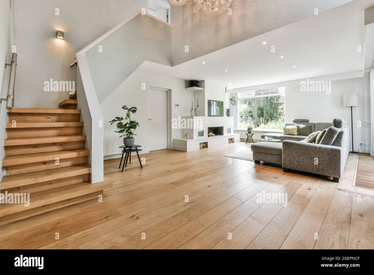 Cozy house interior with a wooden floor, large gray sofa, and stairs ...