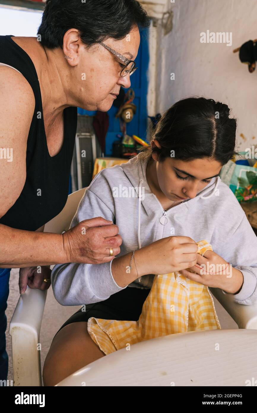 Senior Caucasian Grandmother Teaches Her Granddaughter To Sew With