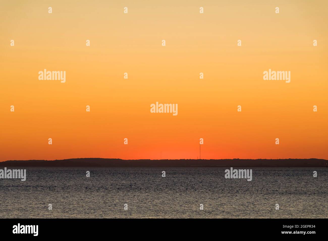 The setting sun lighting up the sky turning it an orange yellowish ...