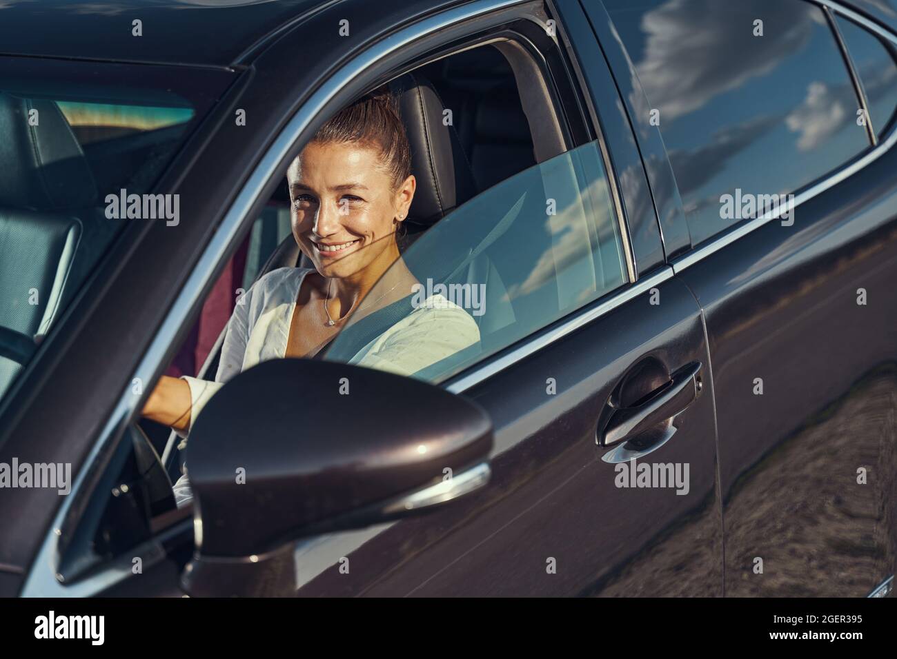 Woman giving a pleased smile from her car Stock Photo - Alamy