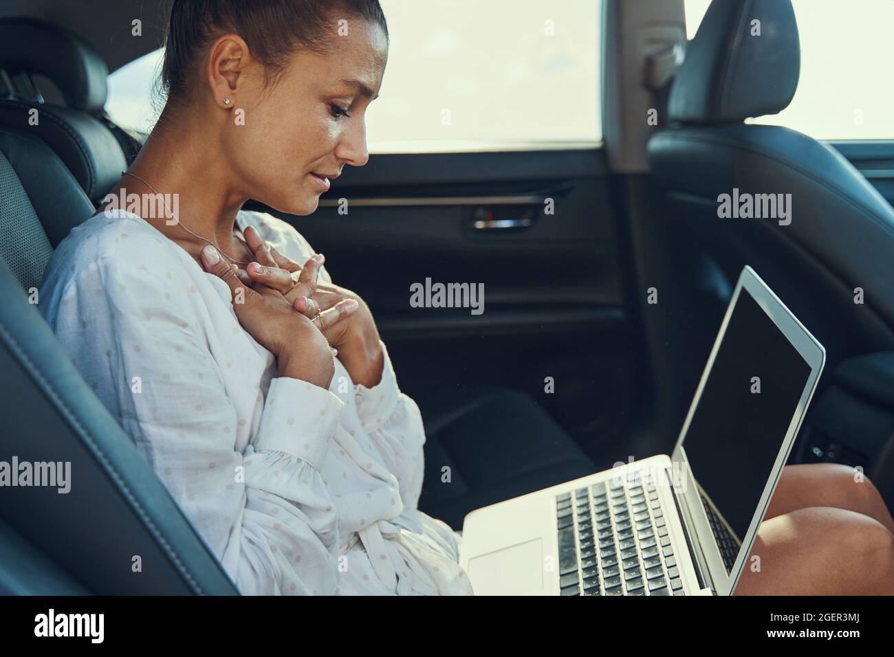 Woman staring at laptop screen while folding hands on chest Stock Photo ...