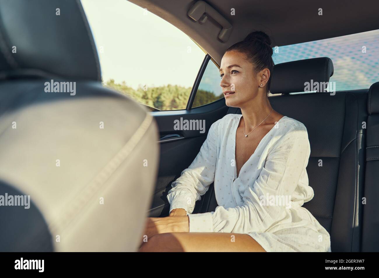 Relaxed lady sitting near window in the back of car Stock Photo - Alamy