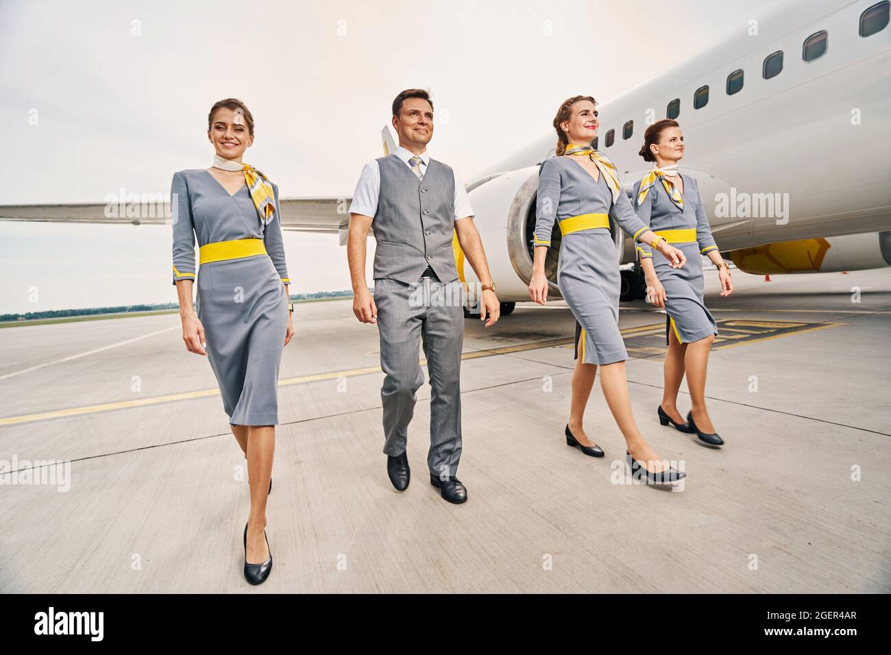 Smiling cabin crew in uniforms walking ahead Stock Photo - Alamy