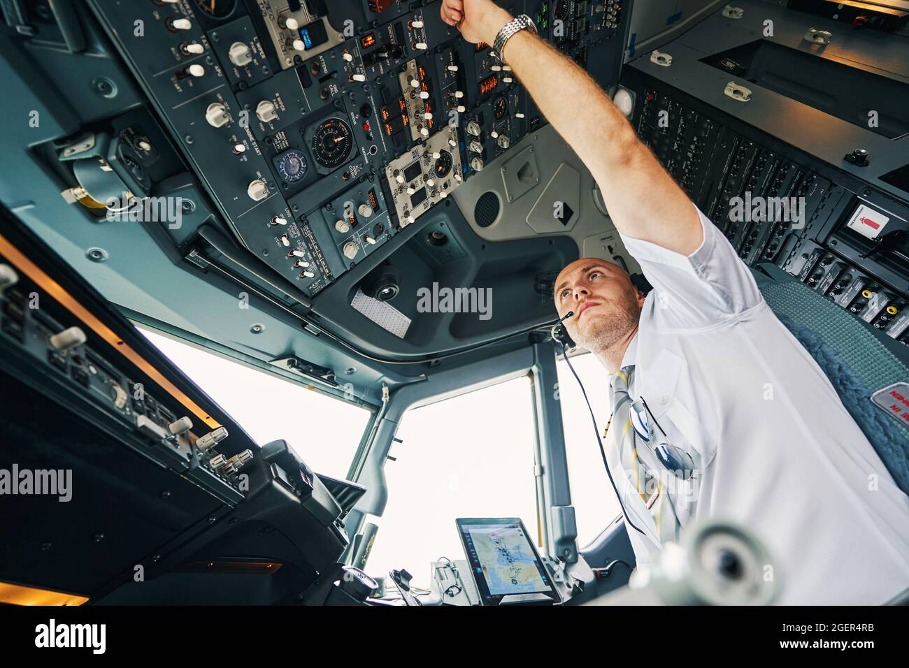 Male pilot flipping a switch on the overhead control panel Stock Photo ...