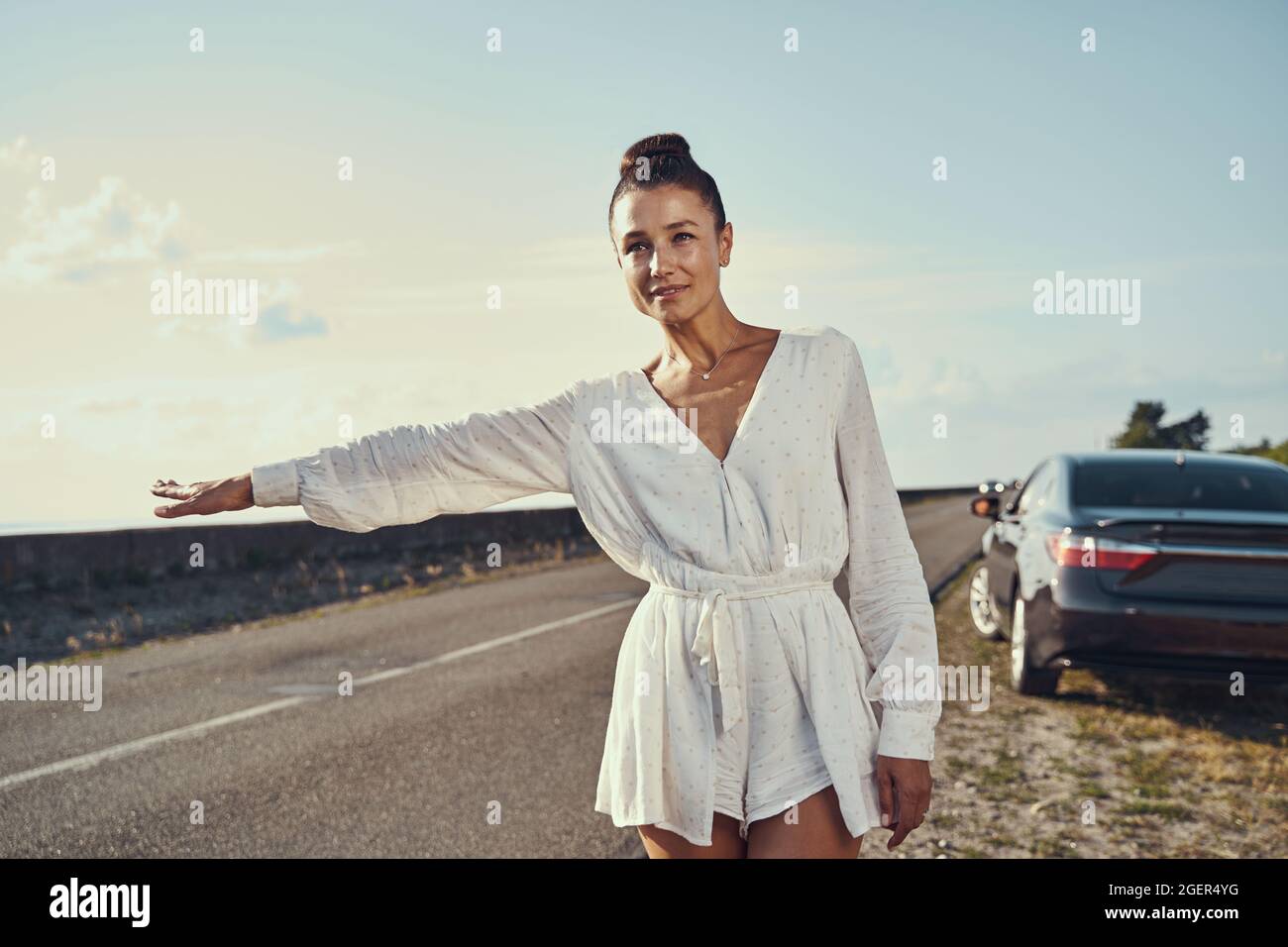 Female in tunic signaling drivers to pick her up Stock Photo - Alamy