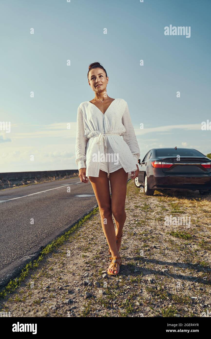 Female walking on curb of road from her auto Stock Photo - Alamy