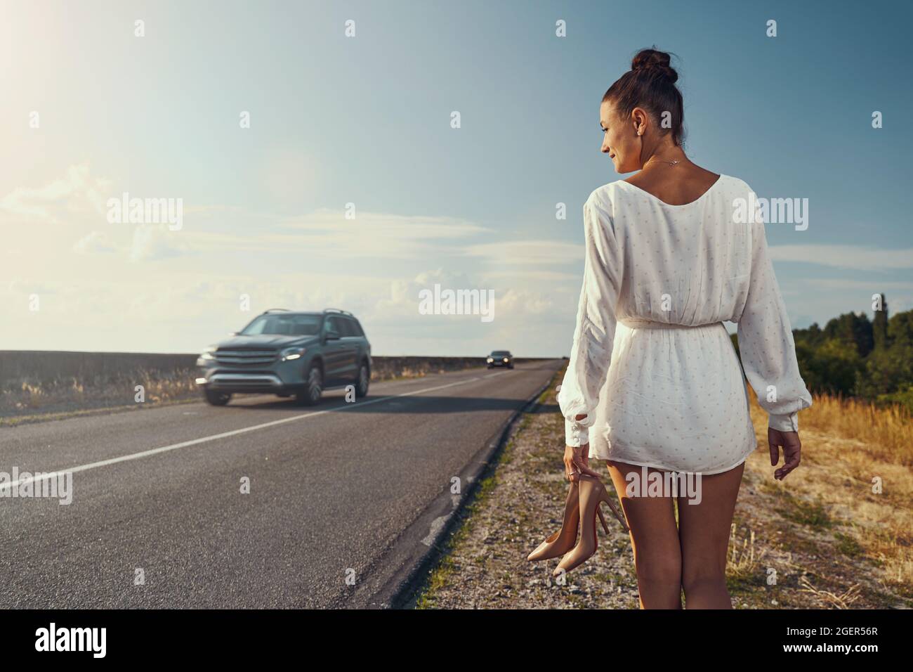 Lady turning from camera and walking along roadside Stock Photo - Alamy