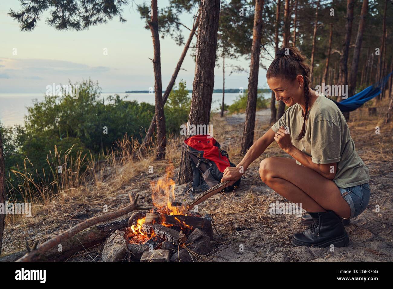 Camper placing branch to burning campfire outdoor Stock Photo - Alamy
