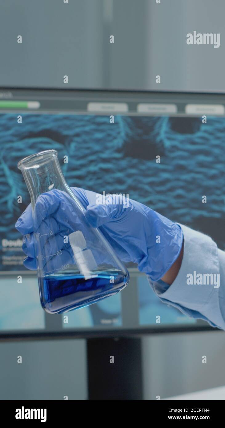 Laboratory scientist analyzing chemical glass beaker with liquid at ...