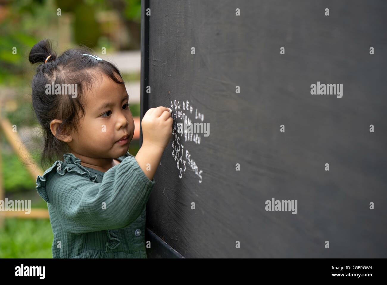 Little Thai girl writing the alphabet on a blackboard Stock Photo - Alamy