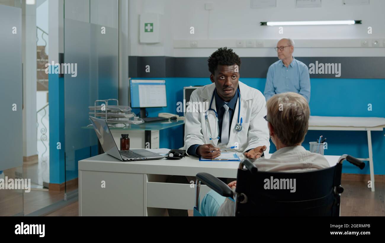 Medic discussing about healthcare with disabled old woman at medical ...