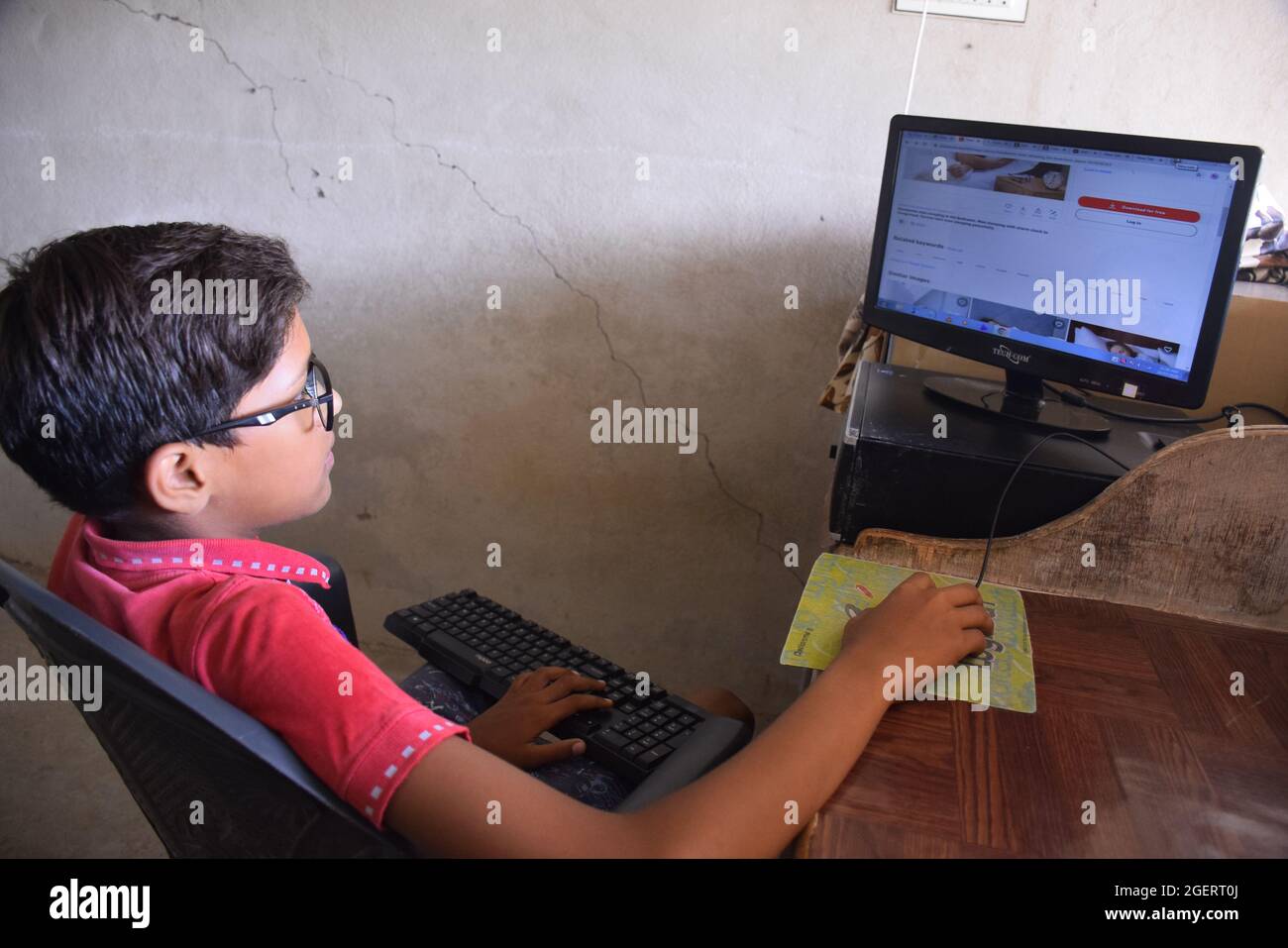 boy operating a computer using mouse and keyboard, He is looking at the ...