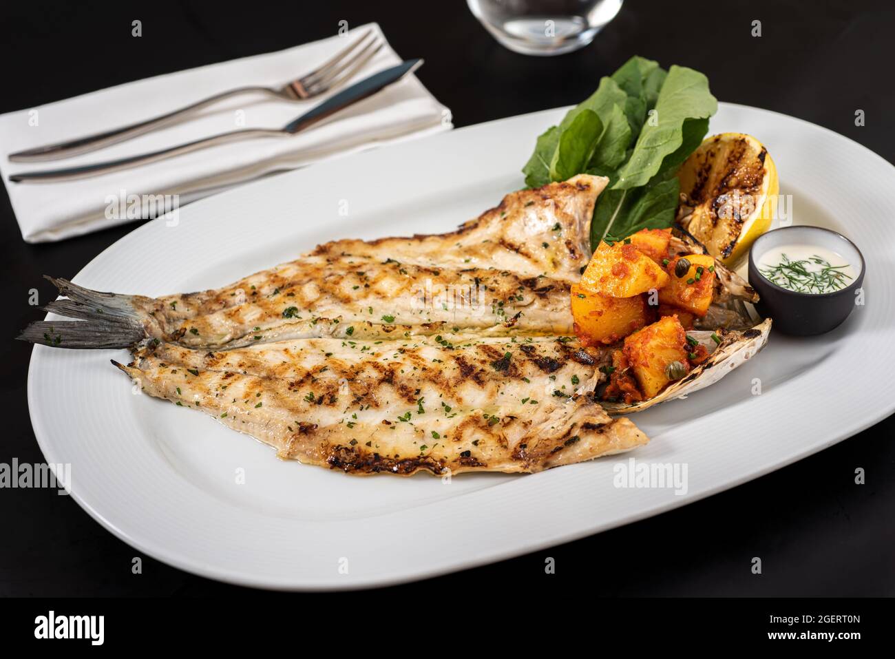 Grilled sea bass and potatoes on a white porcelain plate Stock Photo ...