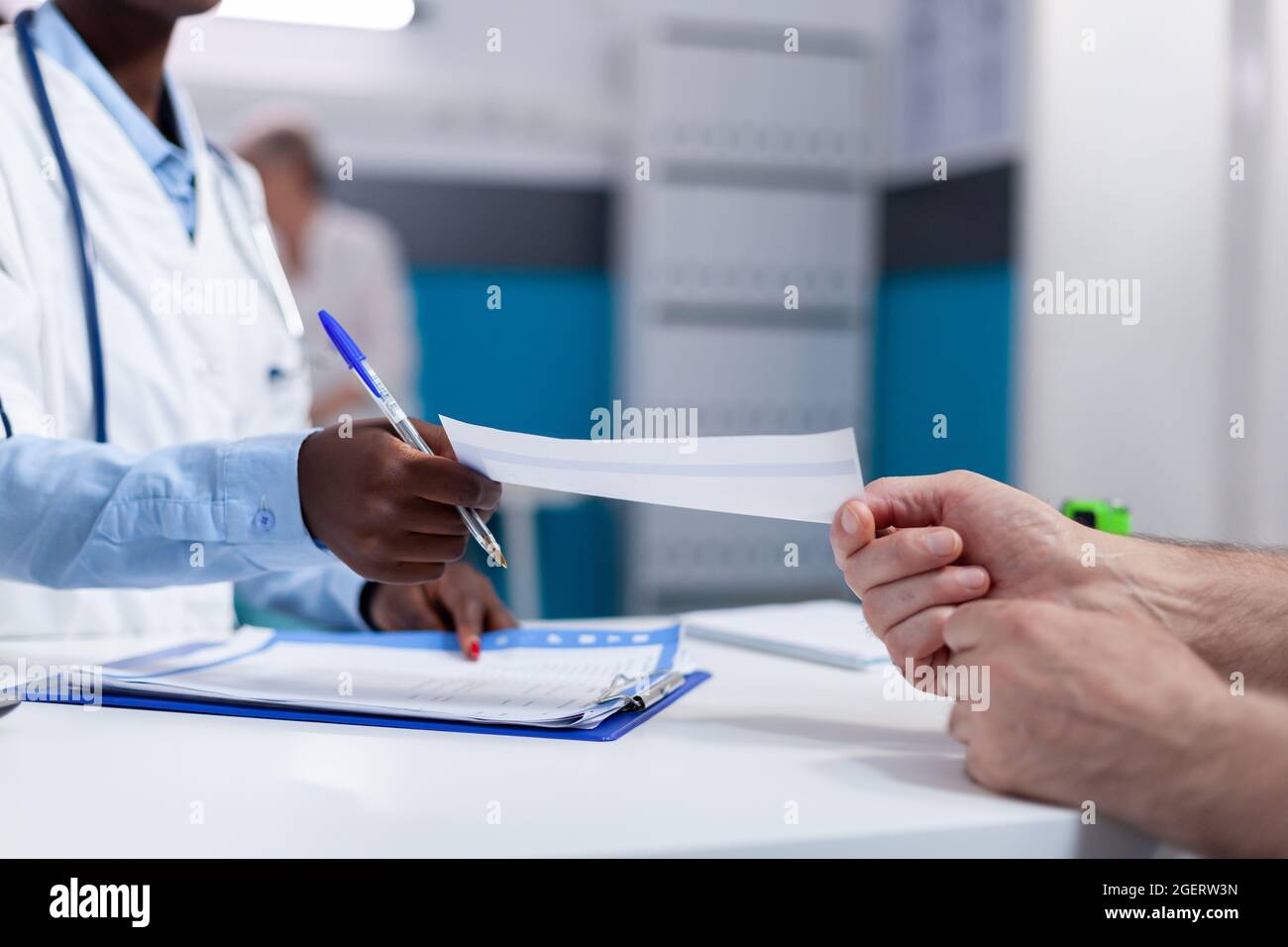 Close up of hand of black doctor handing out paper file to elder ...
