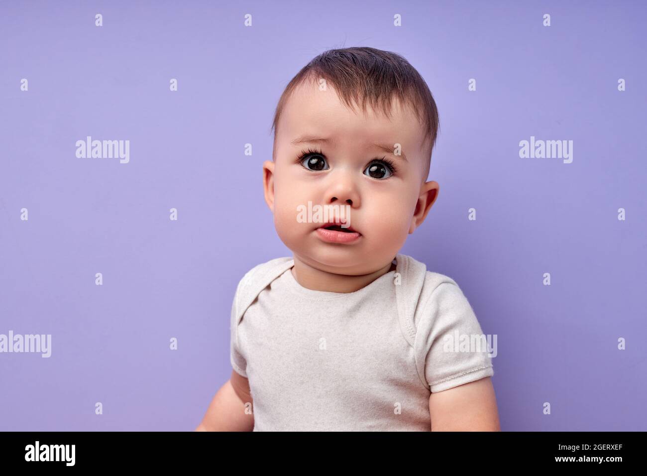 Sweet baby girl is going to cry, looking very cute, isolated on purple ...