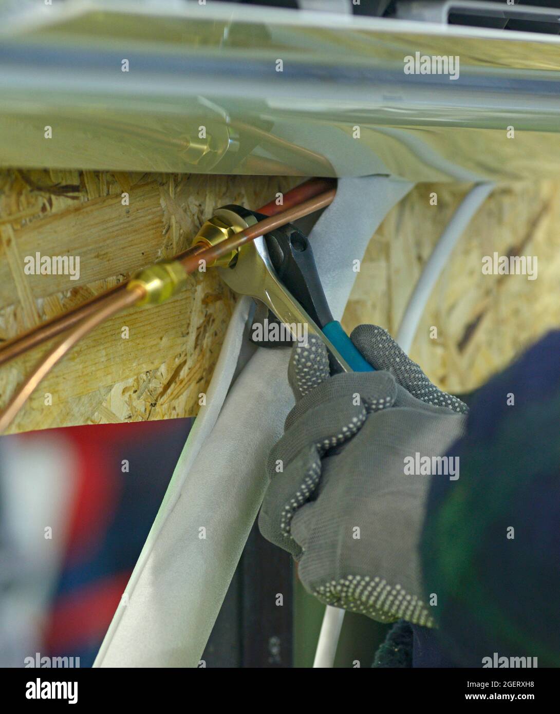 Worker hands in gloves assembling branch pipes of an air conditioner ...