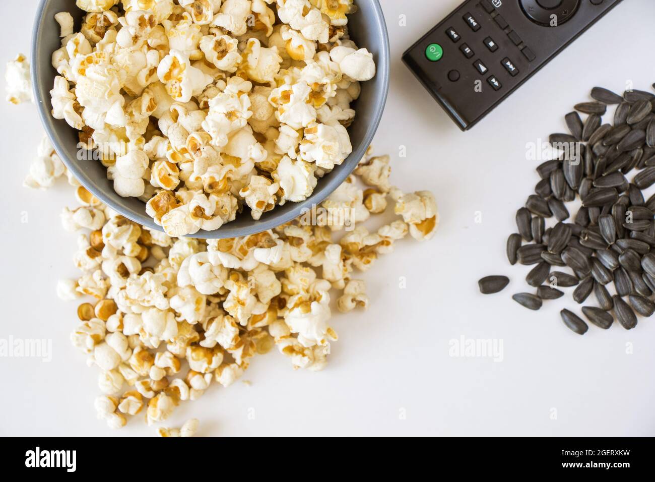 Popcorn and a TV controller on a white background Stock Photo - Alamy