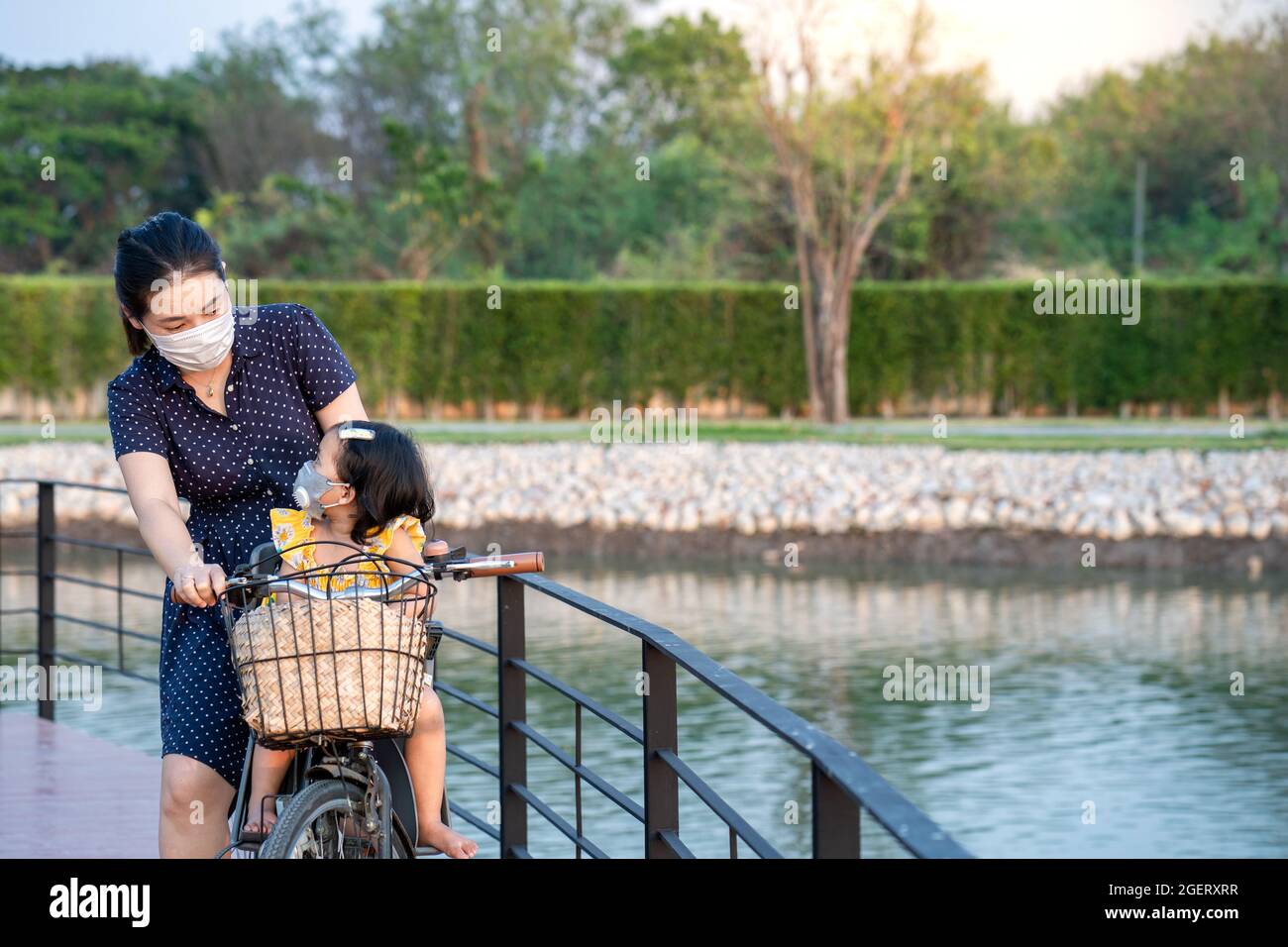 Mother and daughter wearing protective face masks riding a bike in a ...