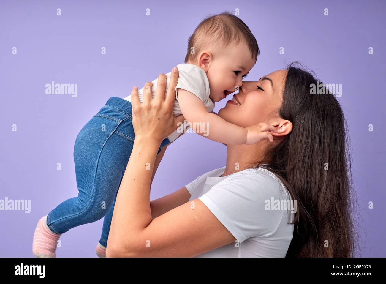 Side view portrait of caucasian woman mother raising baby up, having ...