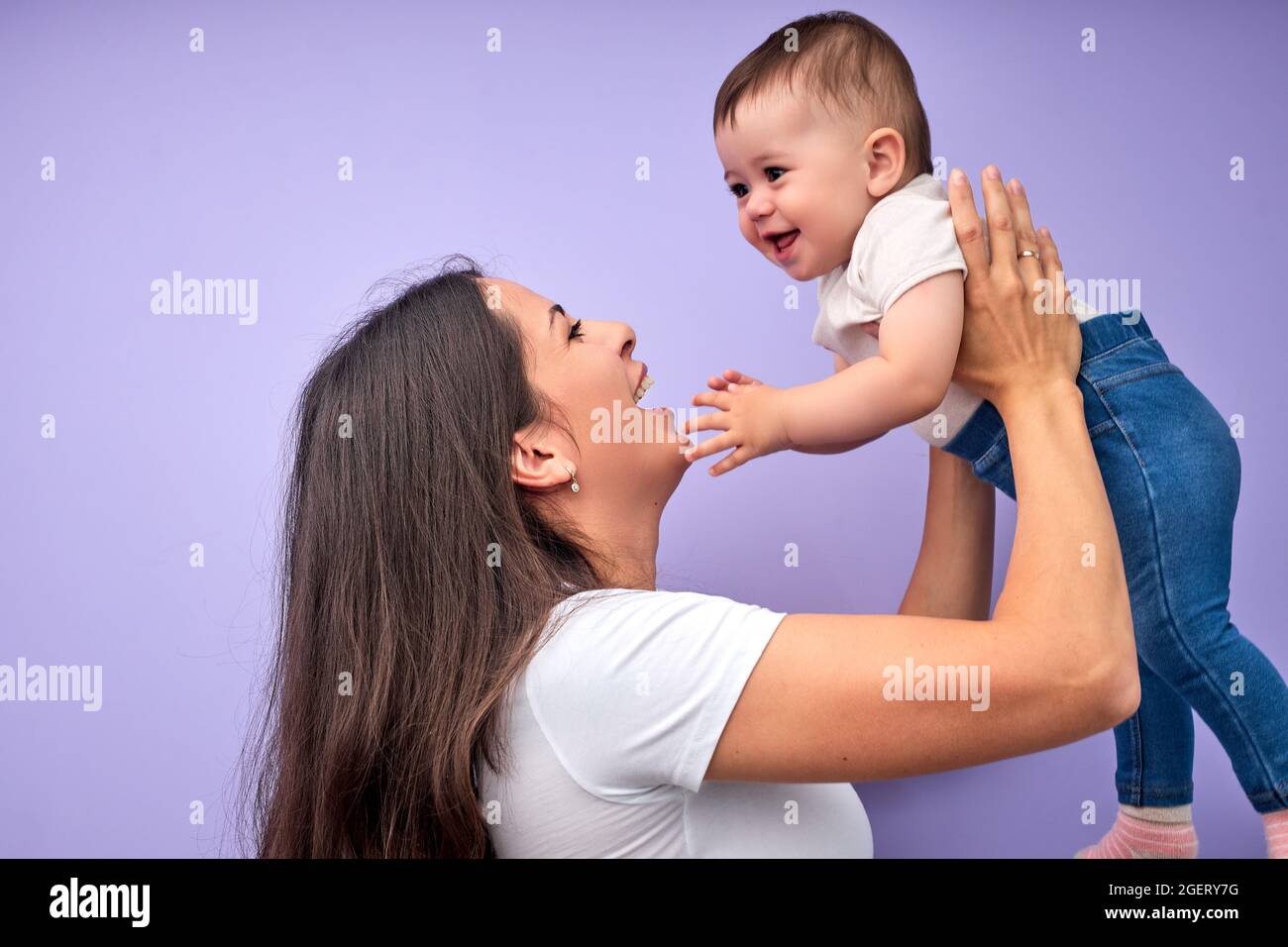 Beautiful young caucasian mother tossing up child baby. Baby laughing ...