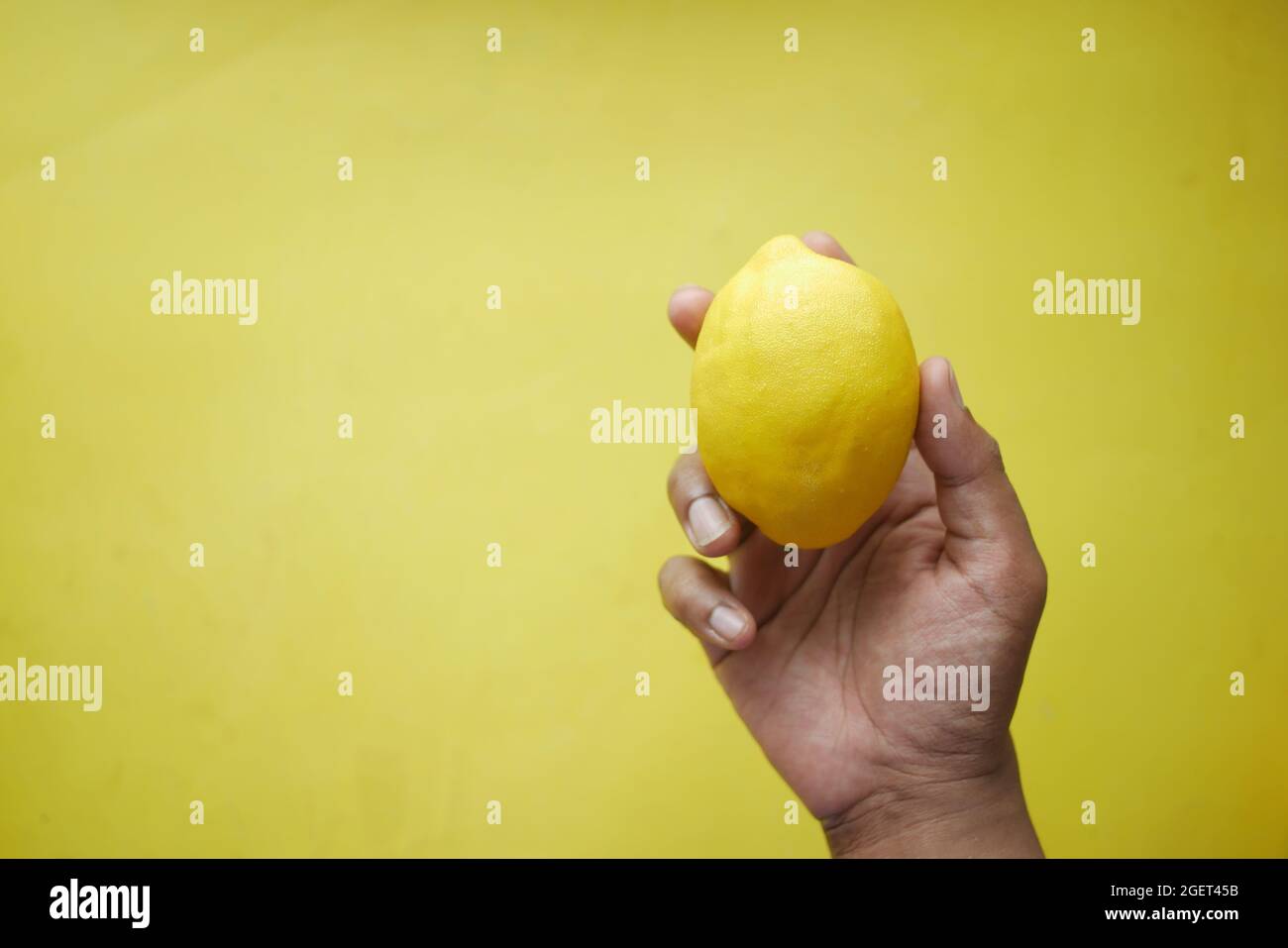hand hold Yellow Lemon on yellow background Stock Photo - Alamy
